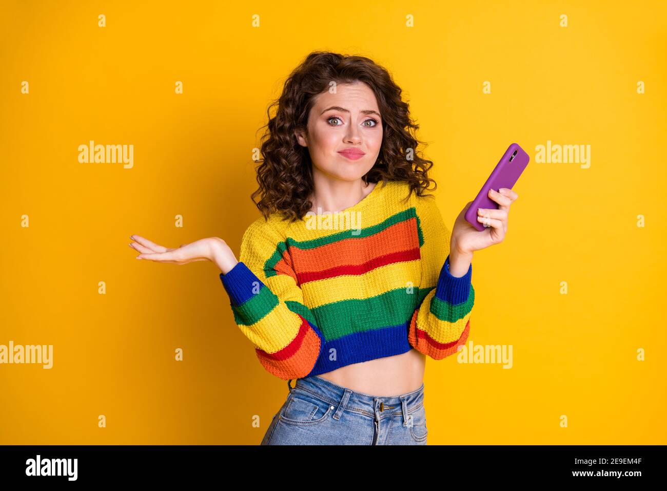 Portrait of uncertain curly hair girl use smartphone shrug shoulders ...