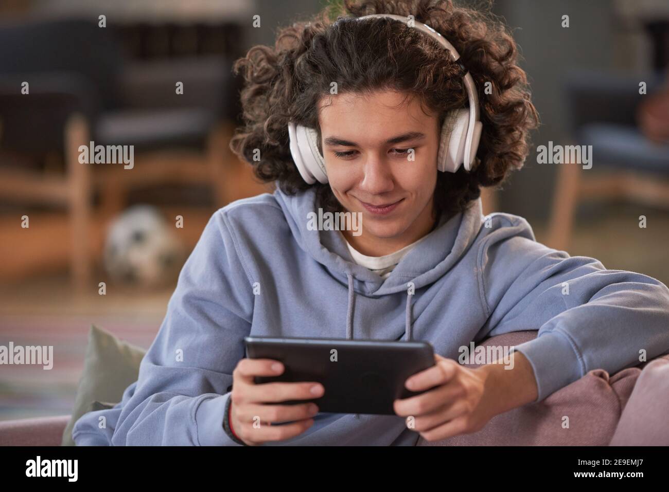 Boy in wireless headphones using his mobile phone for online ...