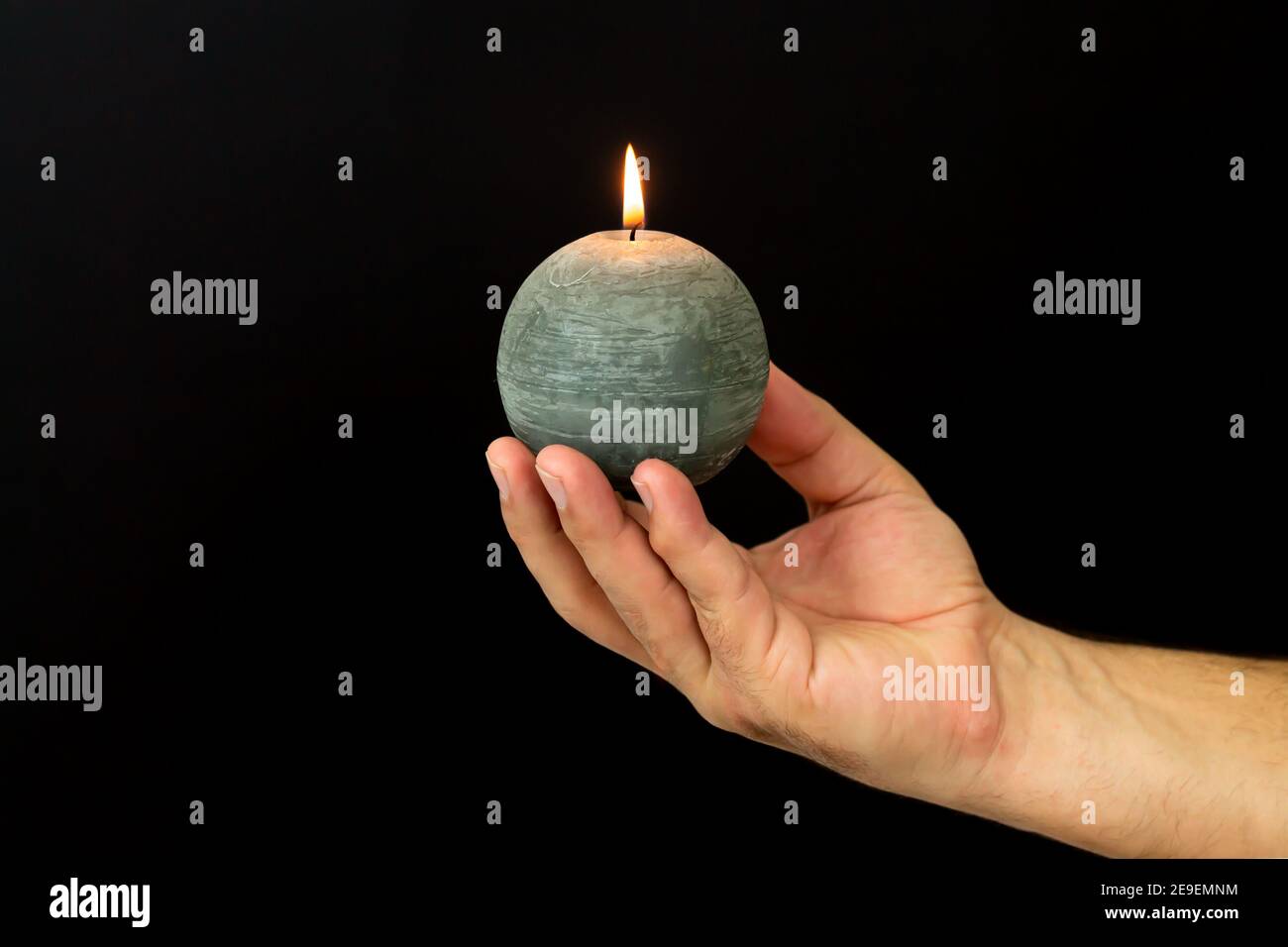 Man holding big burning candle on dark background Stock Photo - Alamy