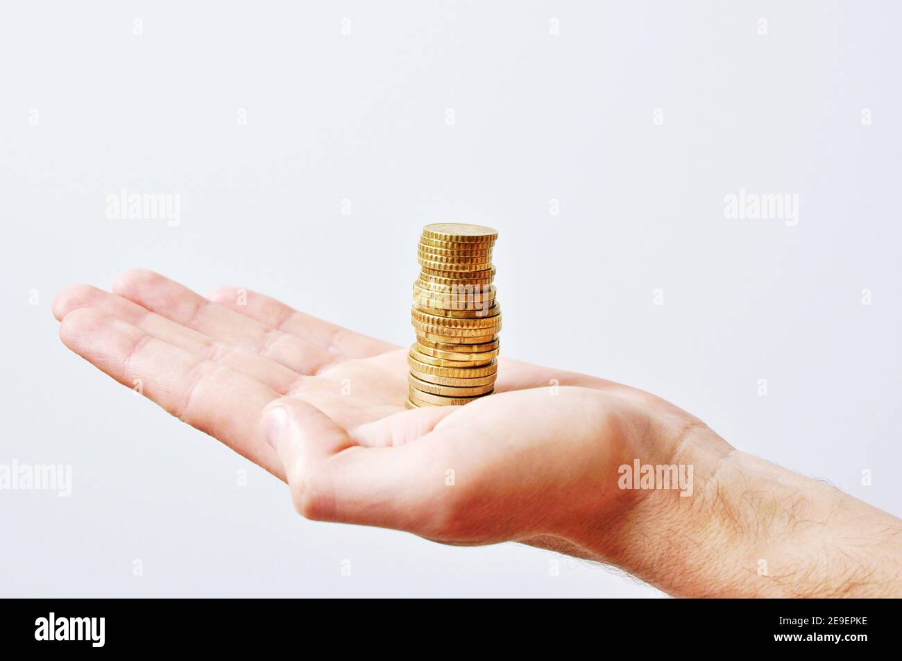 Caucasian men hand holding a money stack (golden coins), on white ...