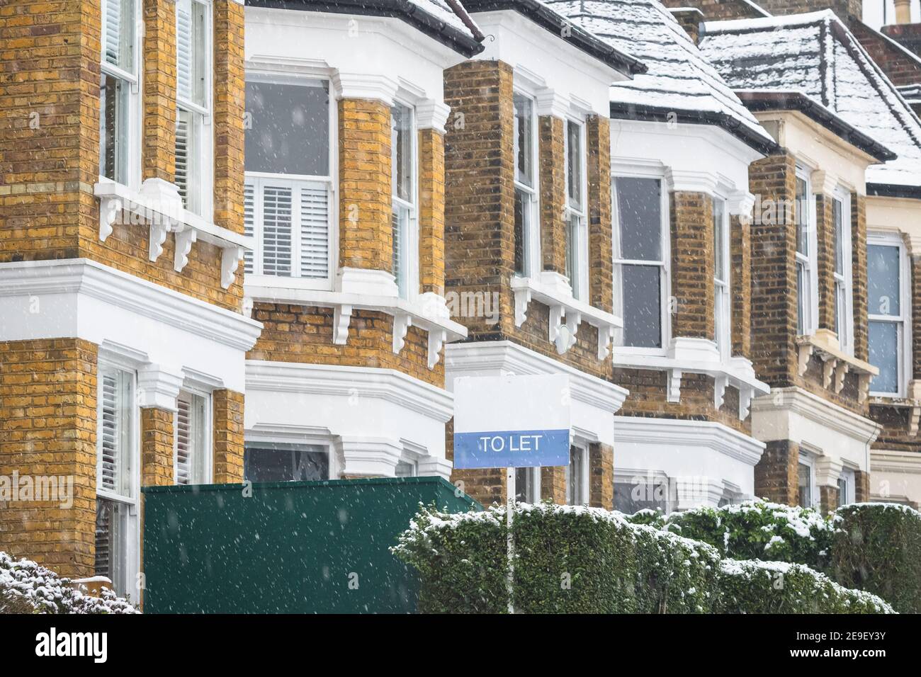 To Let sign displayed outside terrace houses during snowfall around ...