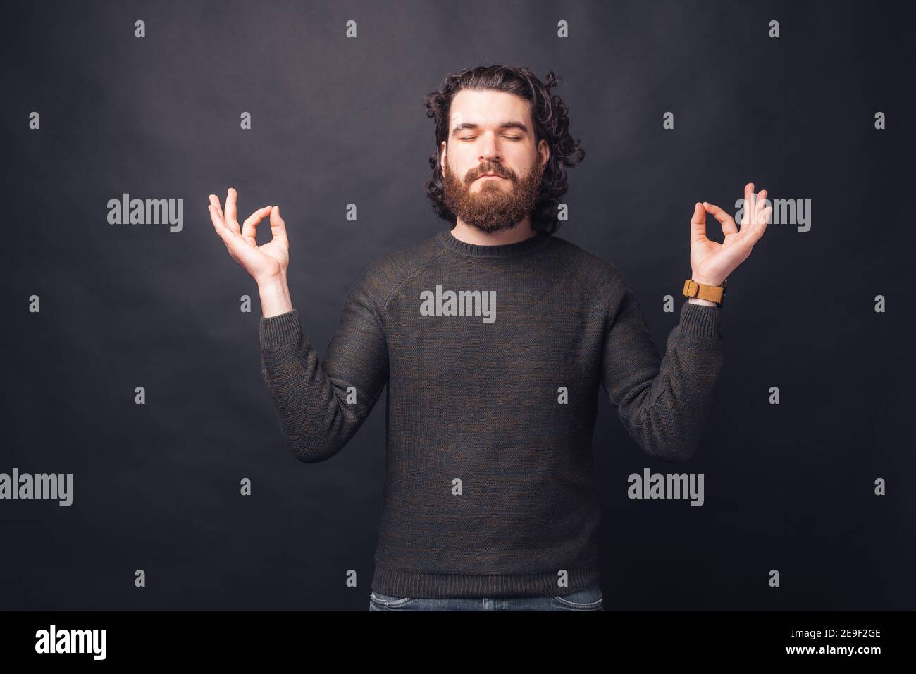 Photo of handsome man with beard in zen posture over black background ...