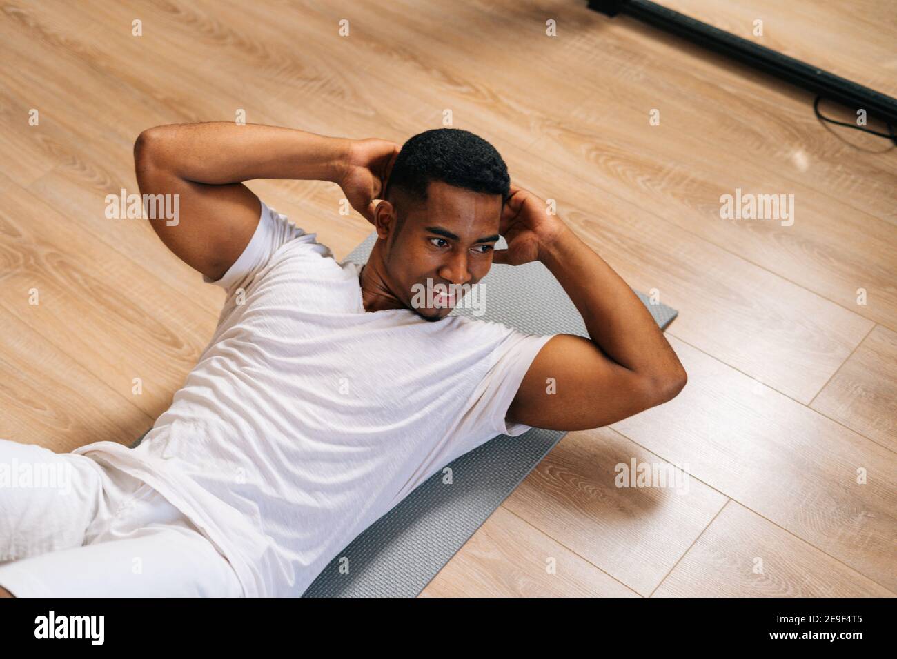 High-angle shot of African-American man practicing abs crunches ...