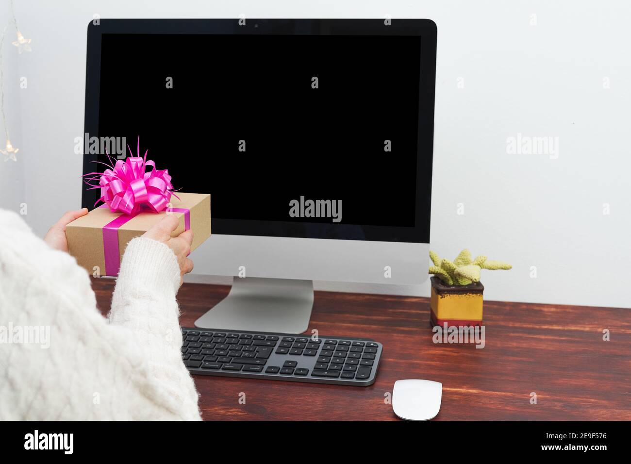 Person delivering a gift in front of the computer. Computer with black ...