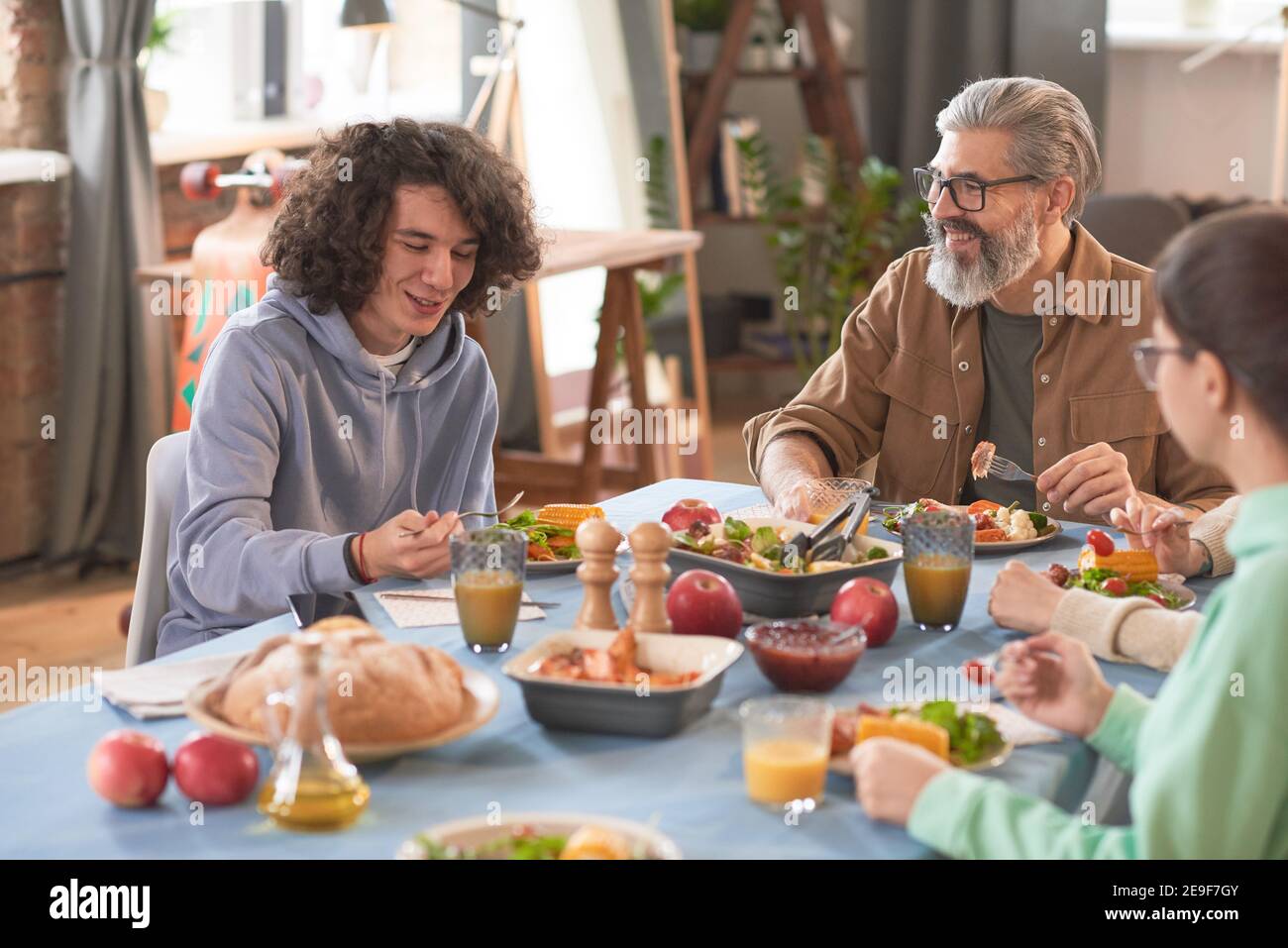 Happy family talking to each other while sitting at the table and ...