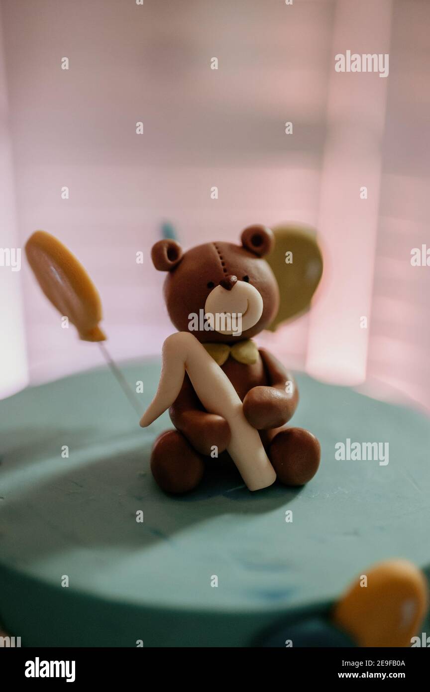 Vertical shot of a kid's birthday cake with a bear decoration holding ...