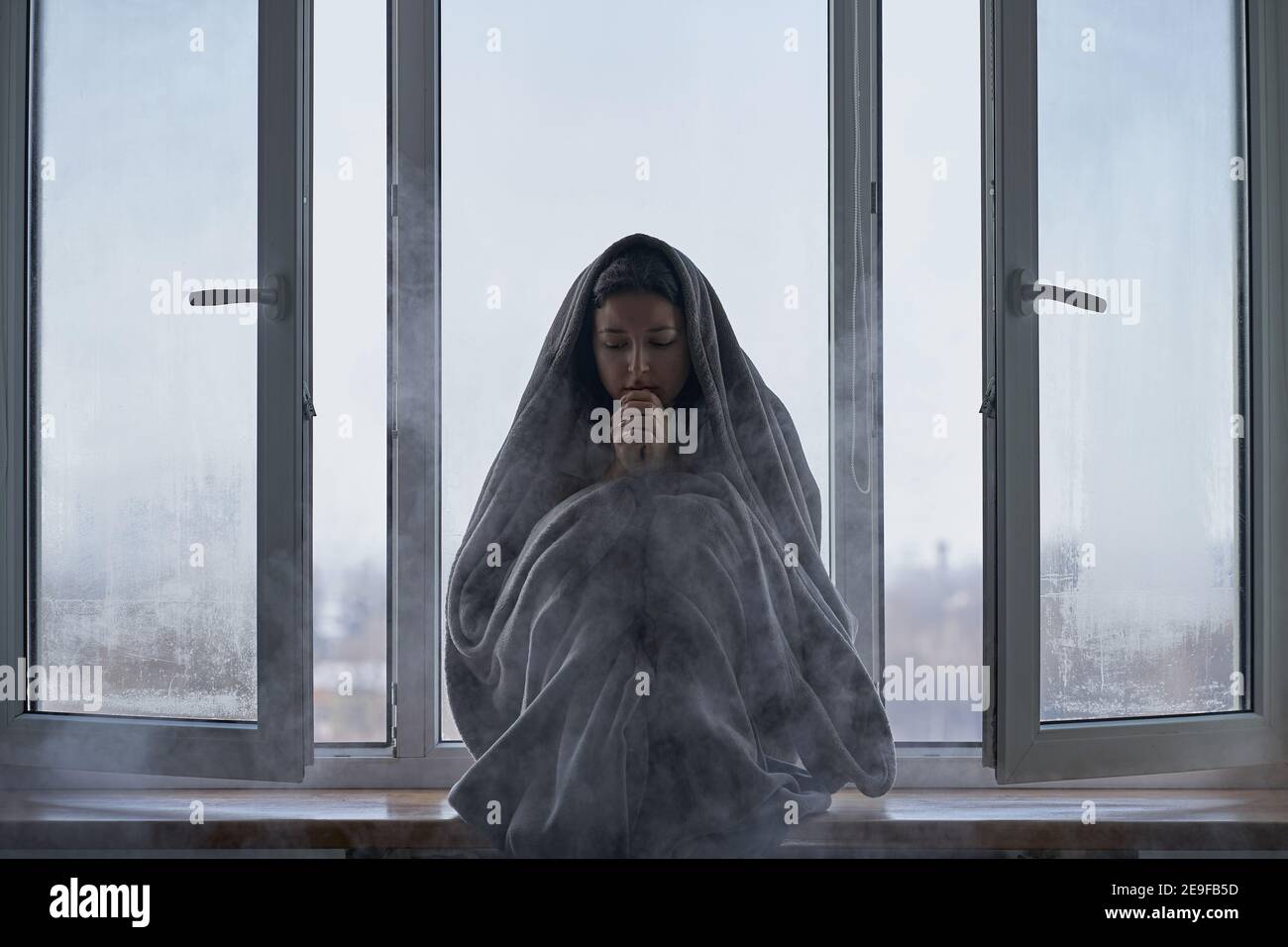 Cold winter weather. A woman is shaking from the cold sitting on the ...
