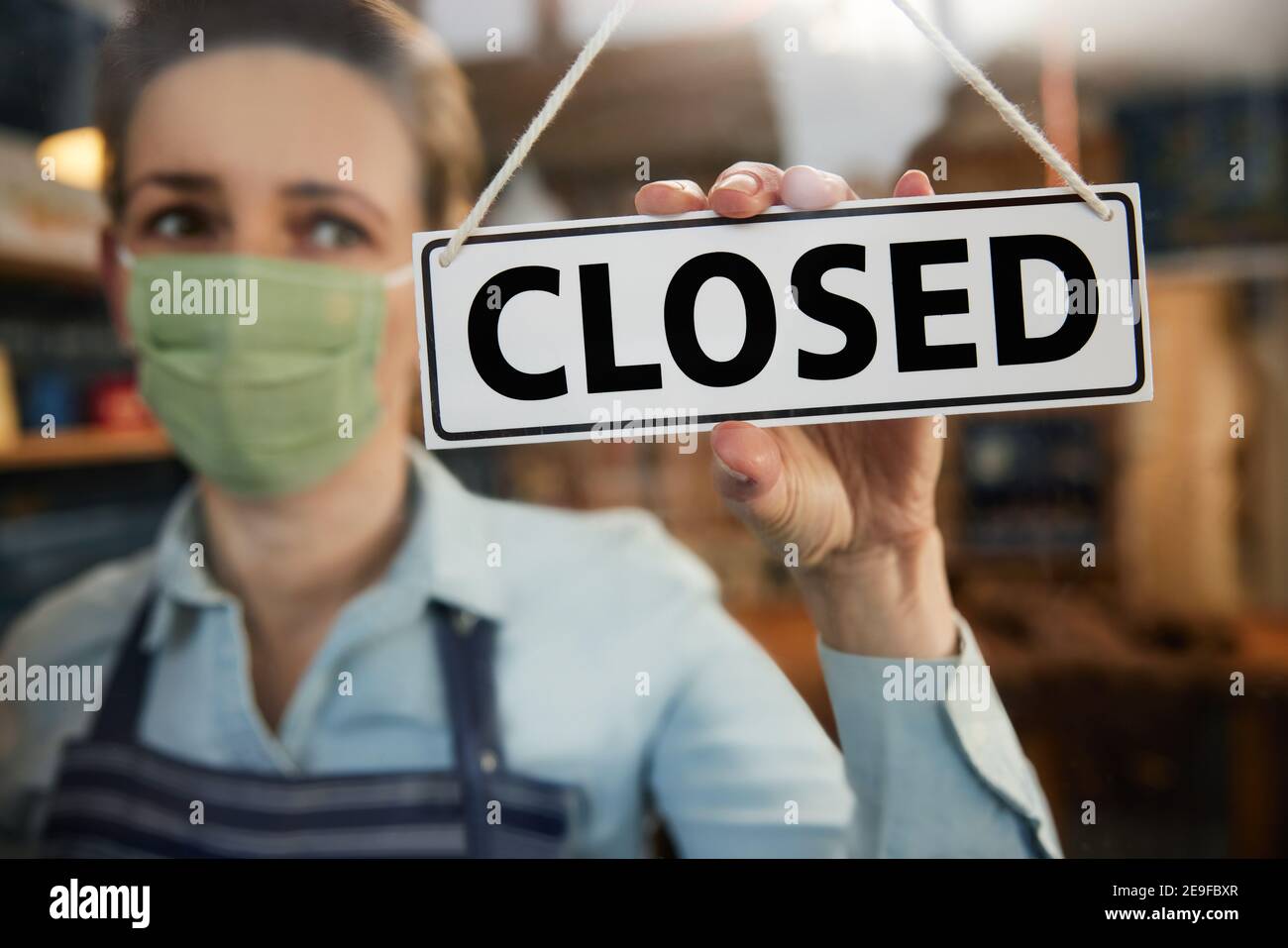 Female Owner Of Small Business Wearing Face Mask Turning Round Closed ...