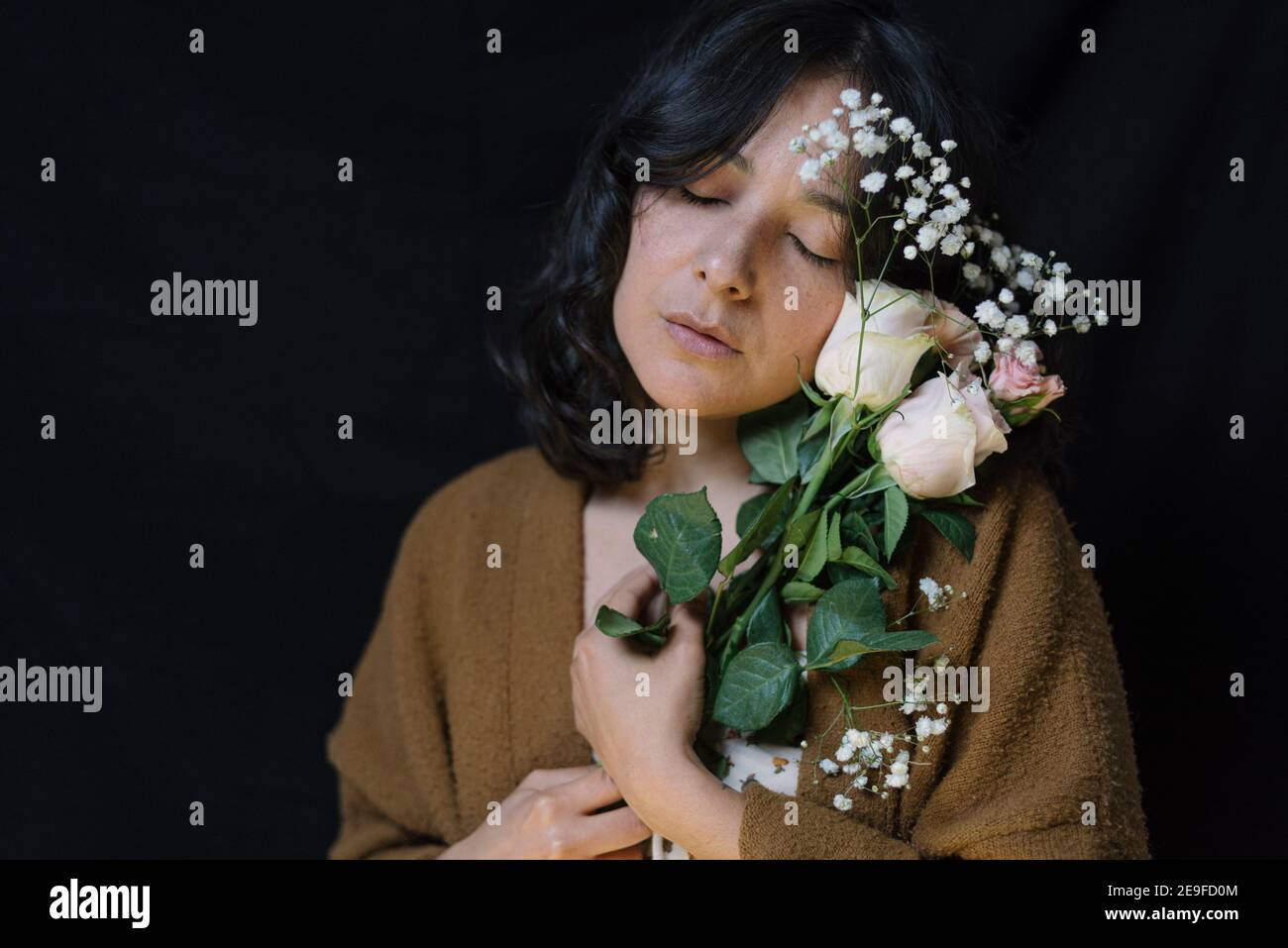 grief concept. woman holding flower bouquet on black background ...