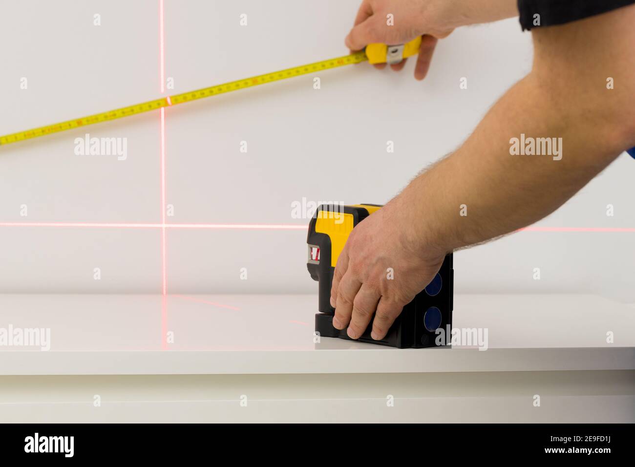 the specialist uses an electronic laser to check right angles and lines ...