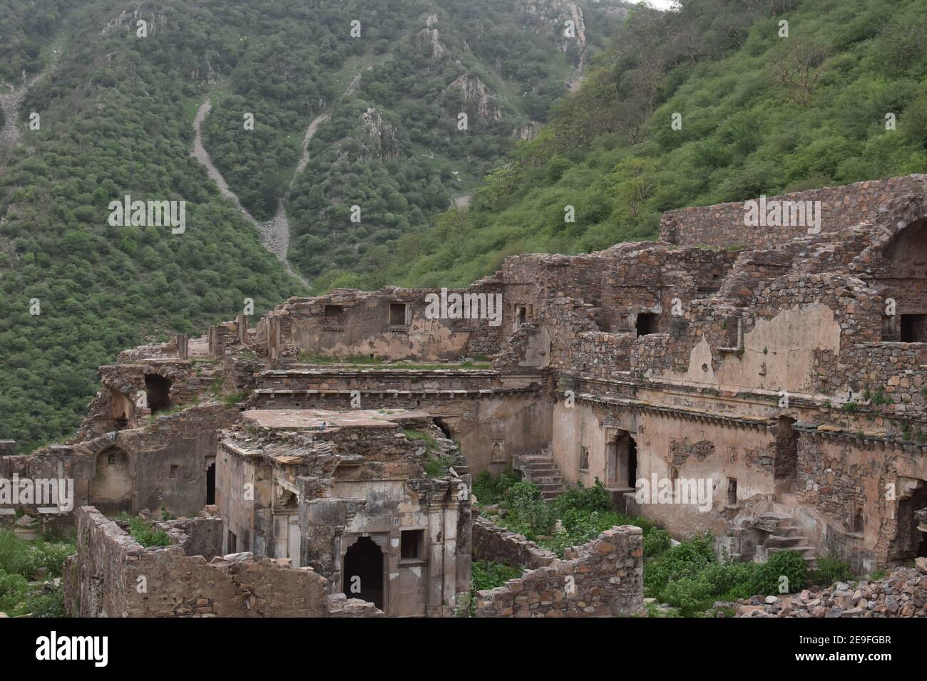 Ruins of an old building near green mountains in Bhangarh village ...
