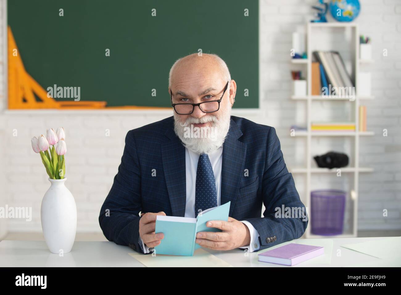 Grey hair professor in empty lecture classroom. School teacher or ...