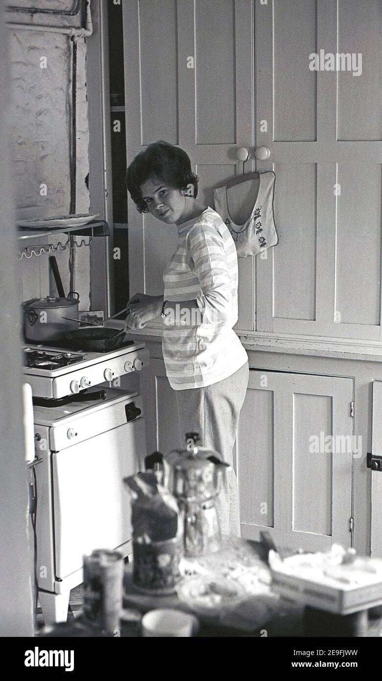1960s, historical, lad in a small kitchen at a stove with a rying pan ...