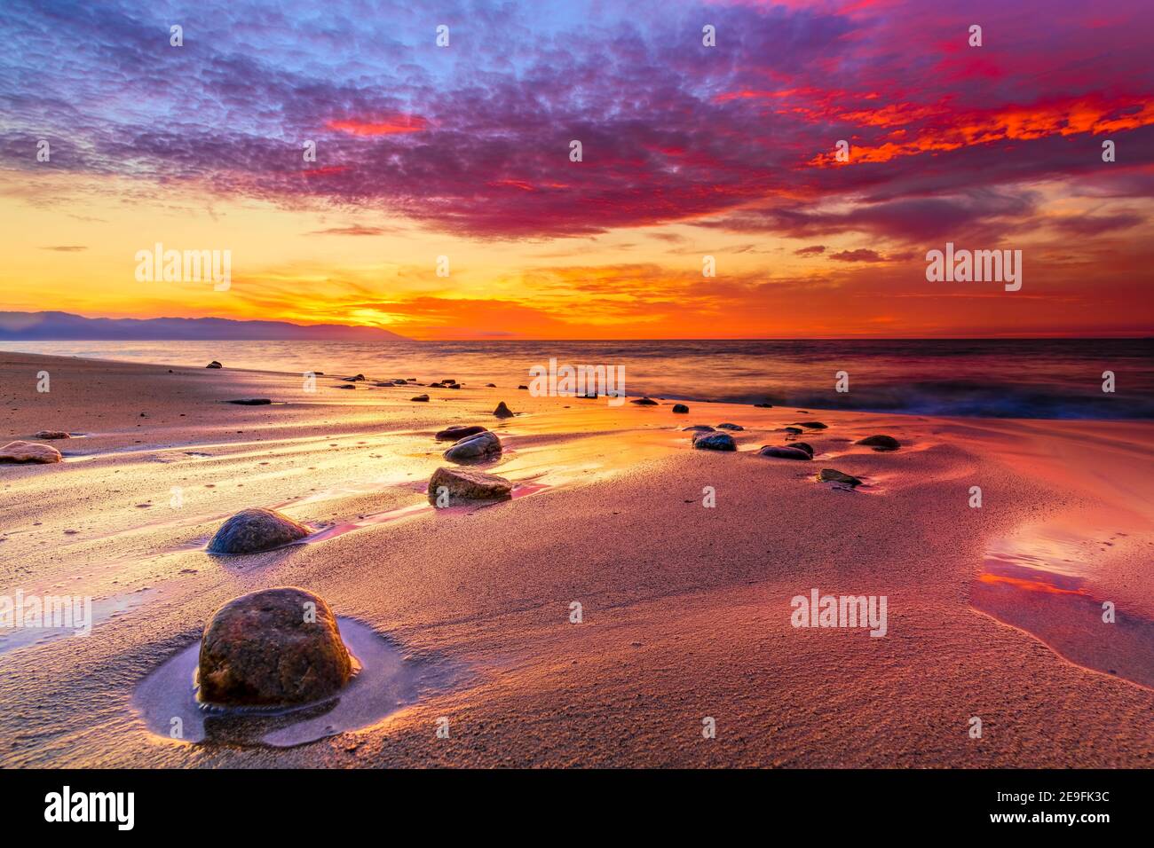 A Colorful Ocean Sunset With Rocks on the Beach and a Vibrant ...