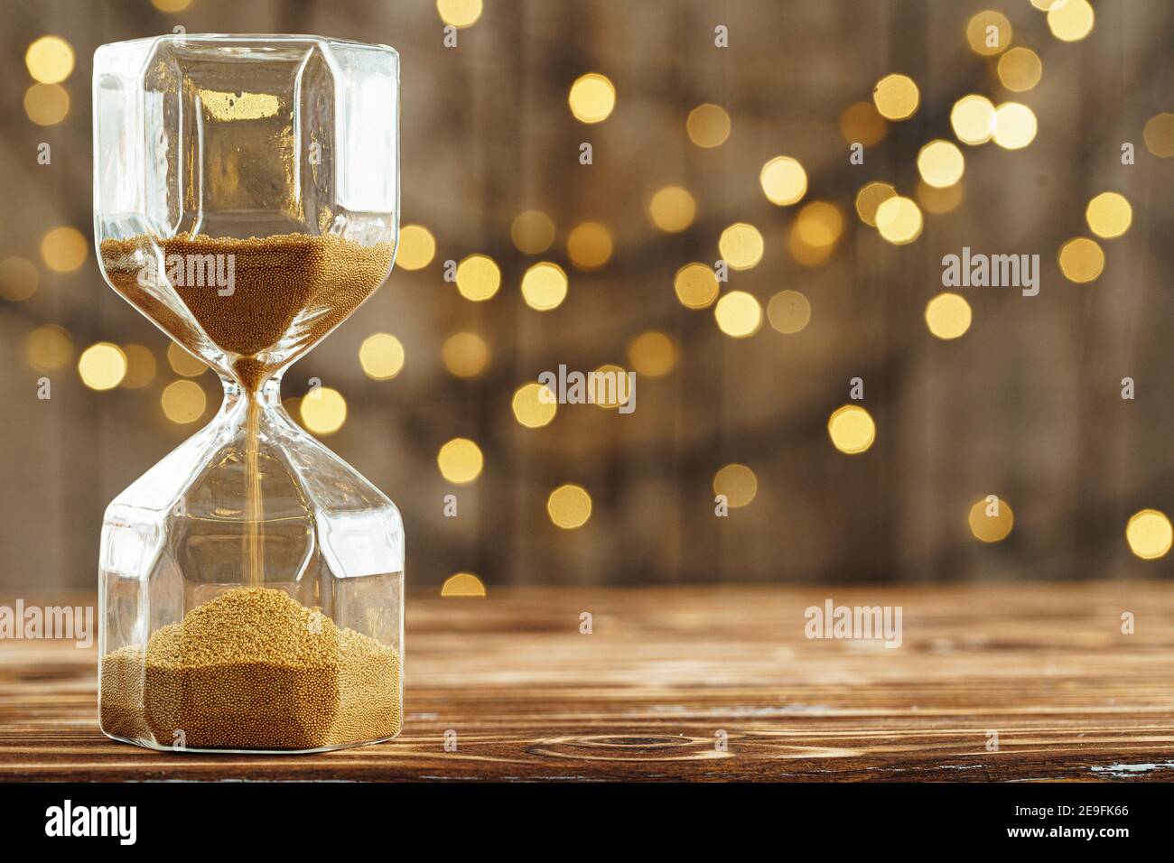 Hourglass on wooden desk against blurred lights Stock Photo - Alamy