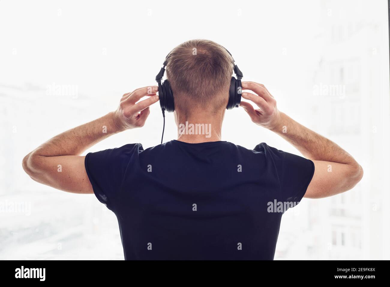 The man in headphones on the background of the window. Back view Stock ...