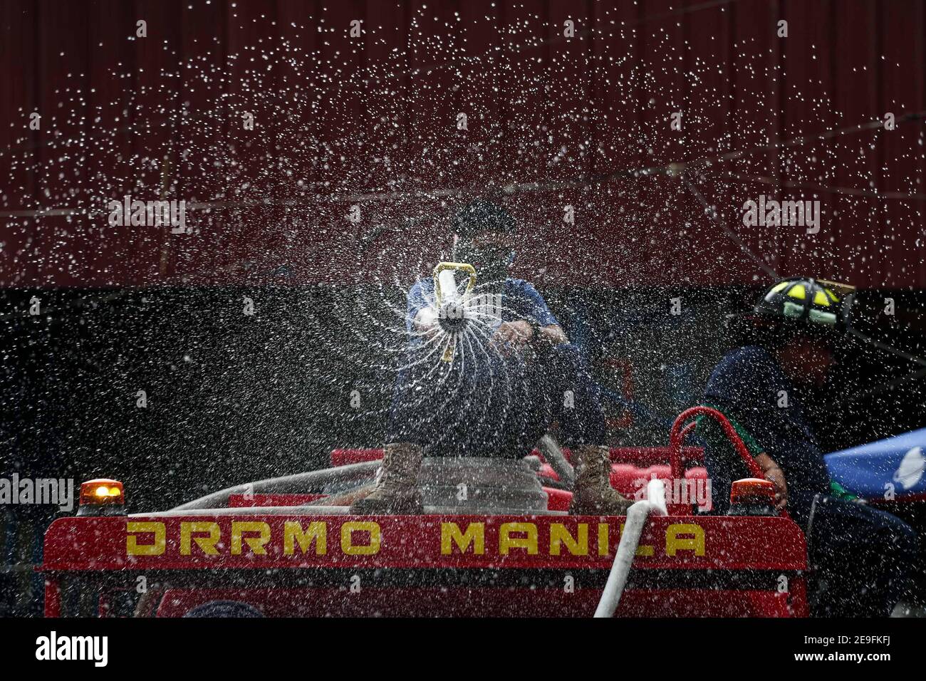 Firemen use a hose to spray disinfectant solution near a public market ...