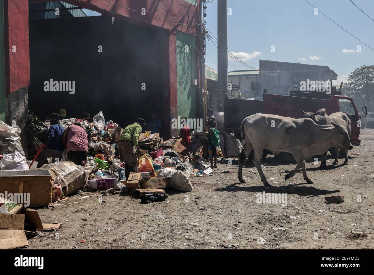 People walk past a garbage site in the town of Rosario in the province ...