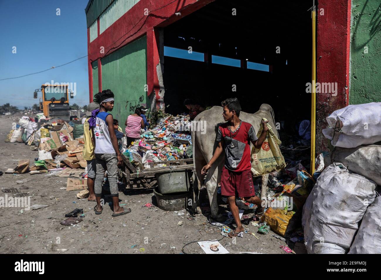 People collect recyclable materials ay a garbage site in the town of ...