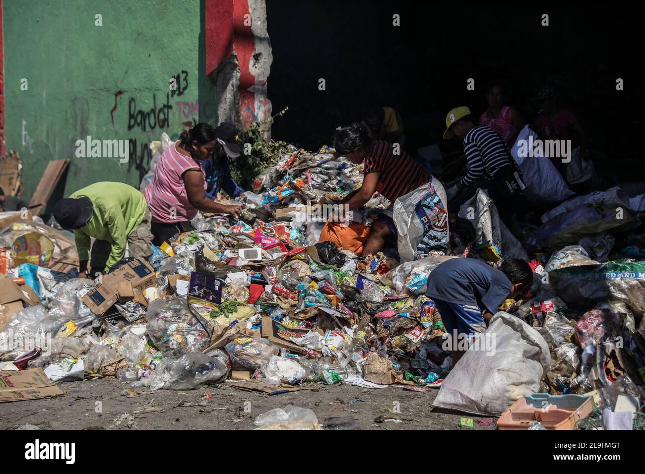 People collect recyclable materials ay a garbage site in the town of ...