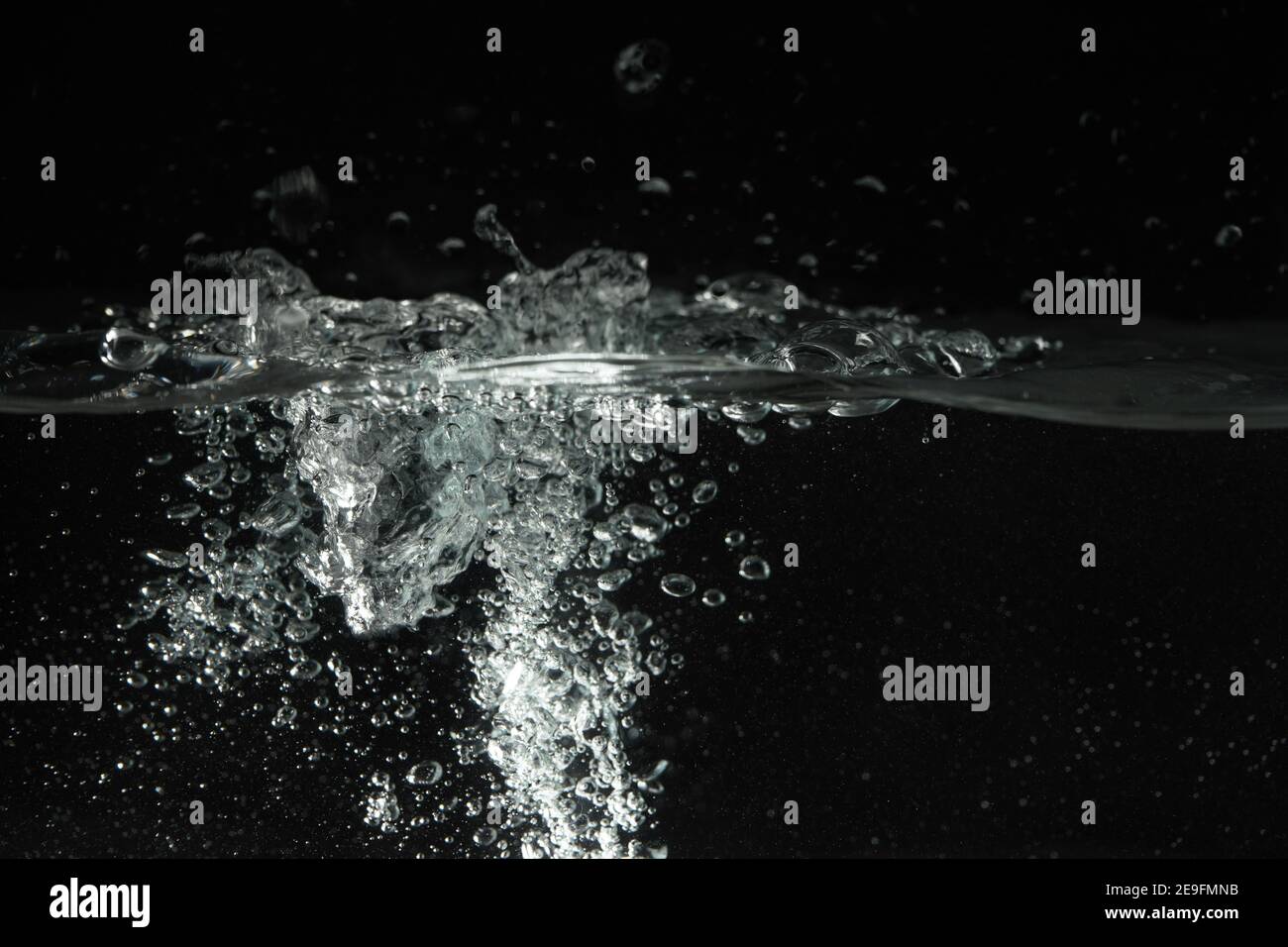 Water splashing as it's poured into aquarium tank, black background ...