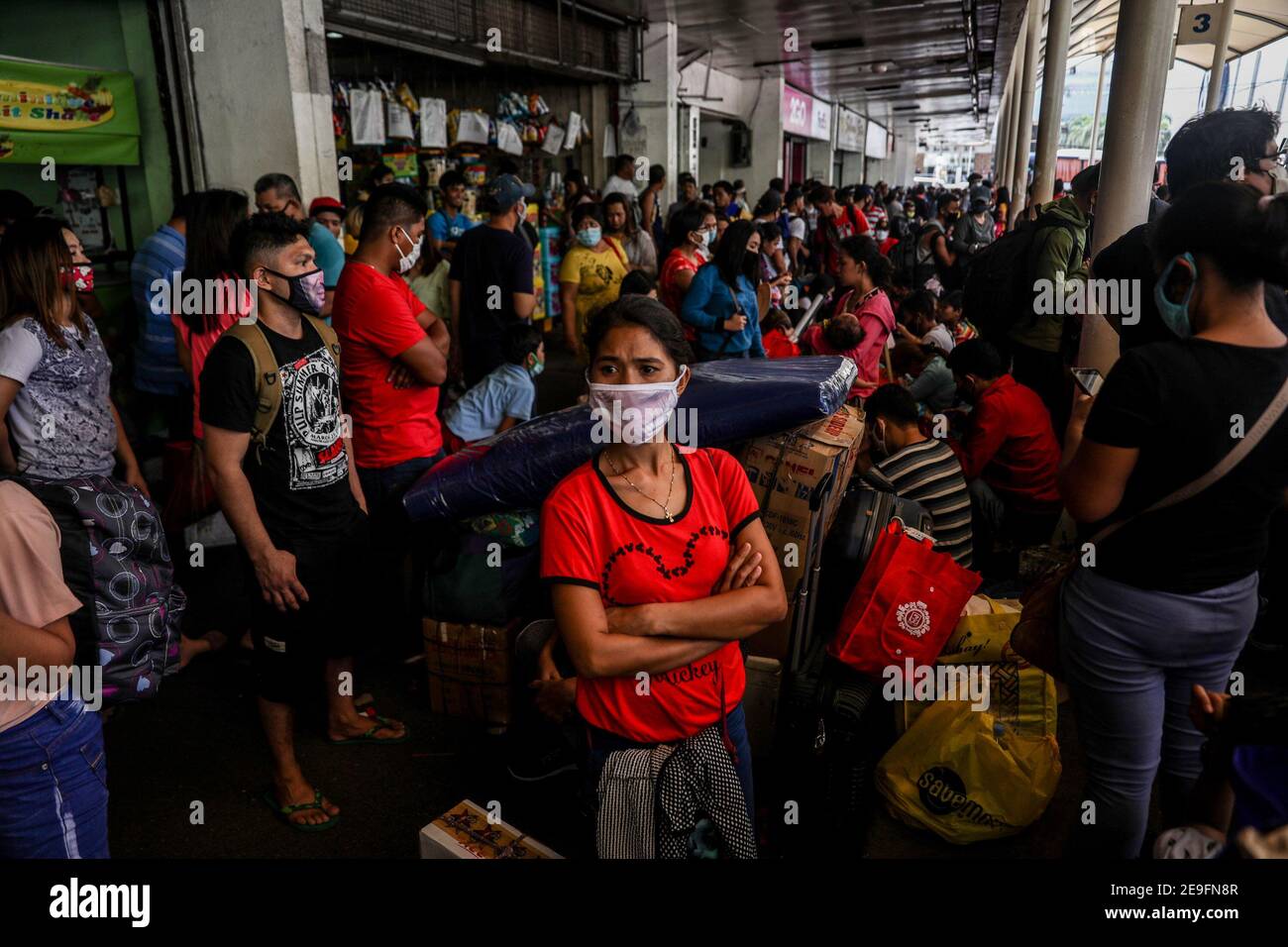 People wearing protective masks flock to a bus terminal during a COVID ...