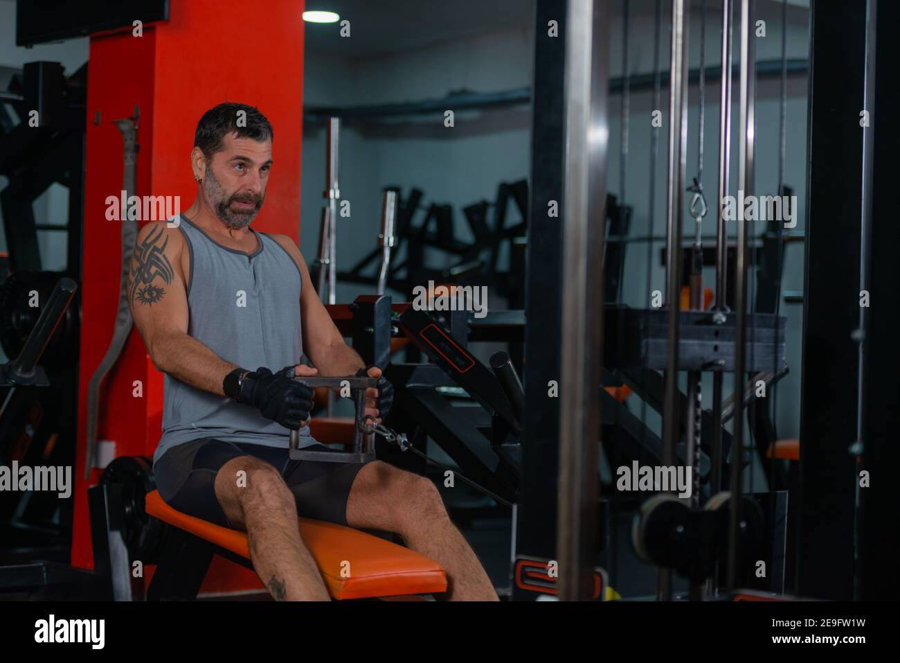 Fitness training in sport gym of active male with beard sitting and ...