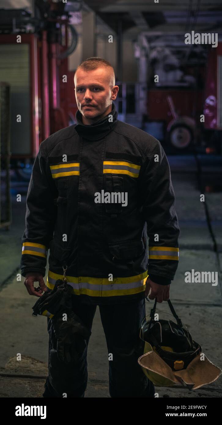 Portrait of young fireman standing inside the fire station Stock Photo ...