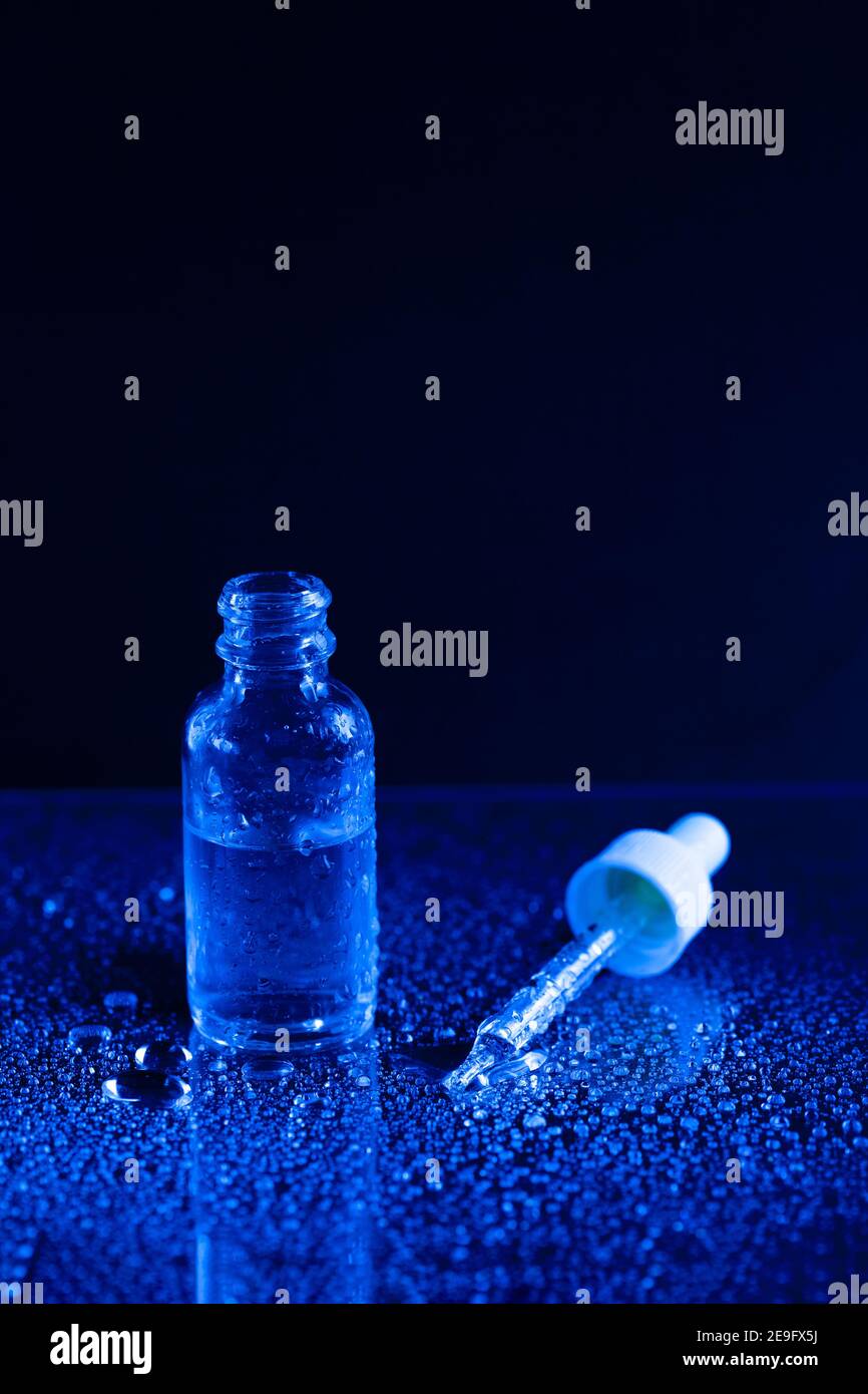 Glass tincture bottle with medicine dropper on black and blue ...