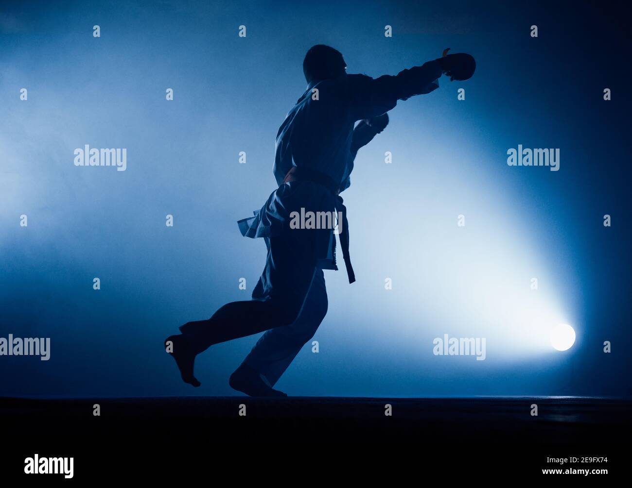 Strong fit athlete, karate man or fighter in white kimono, suit, with ...