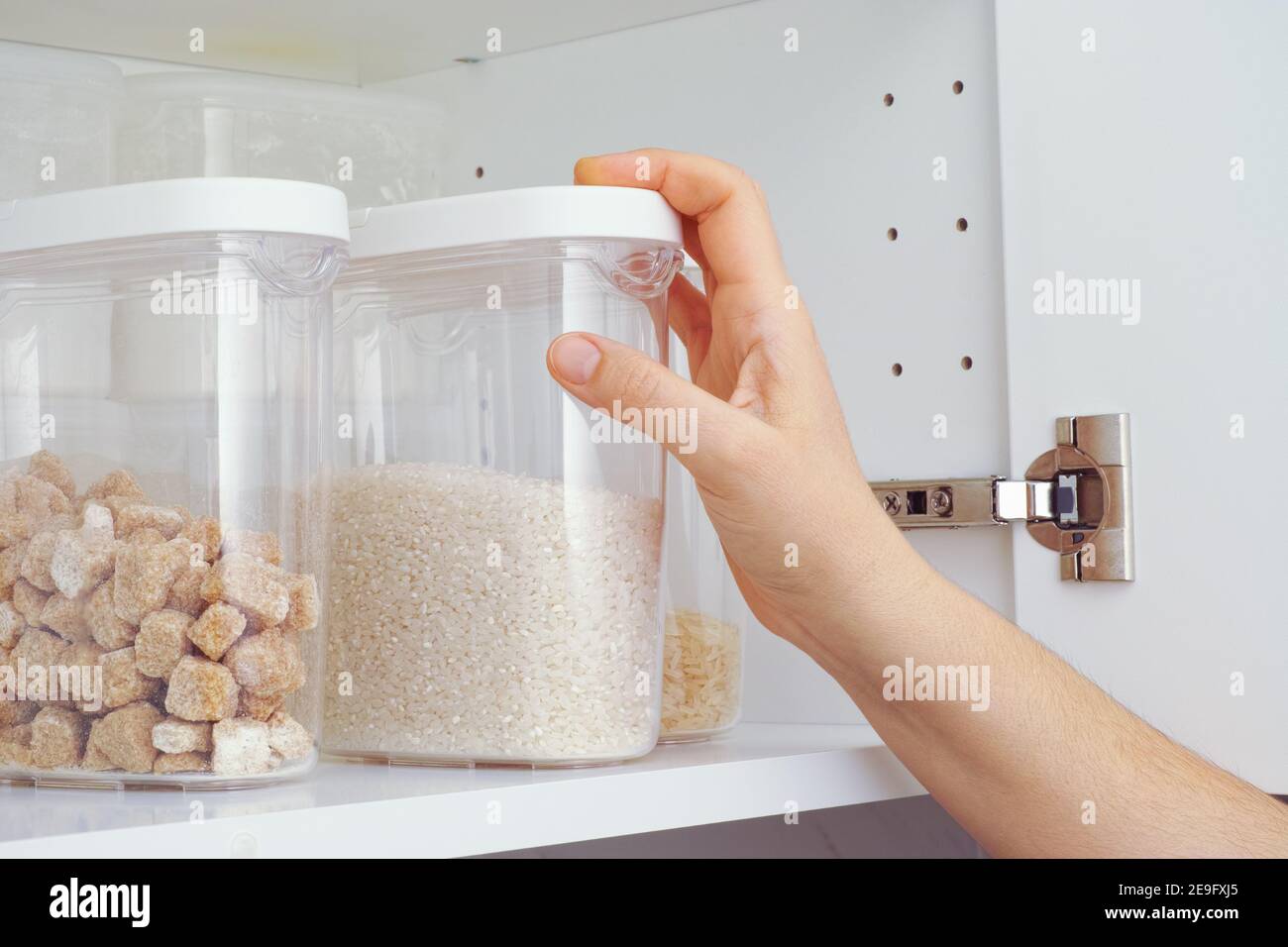 Woman taking rice from a kitchen cupboard. Close up Stock Photo - Alamy