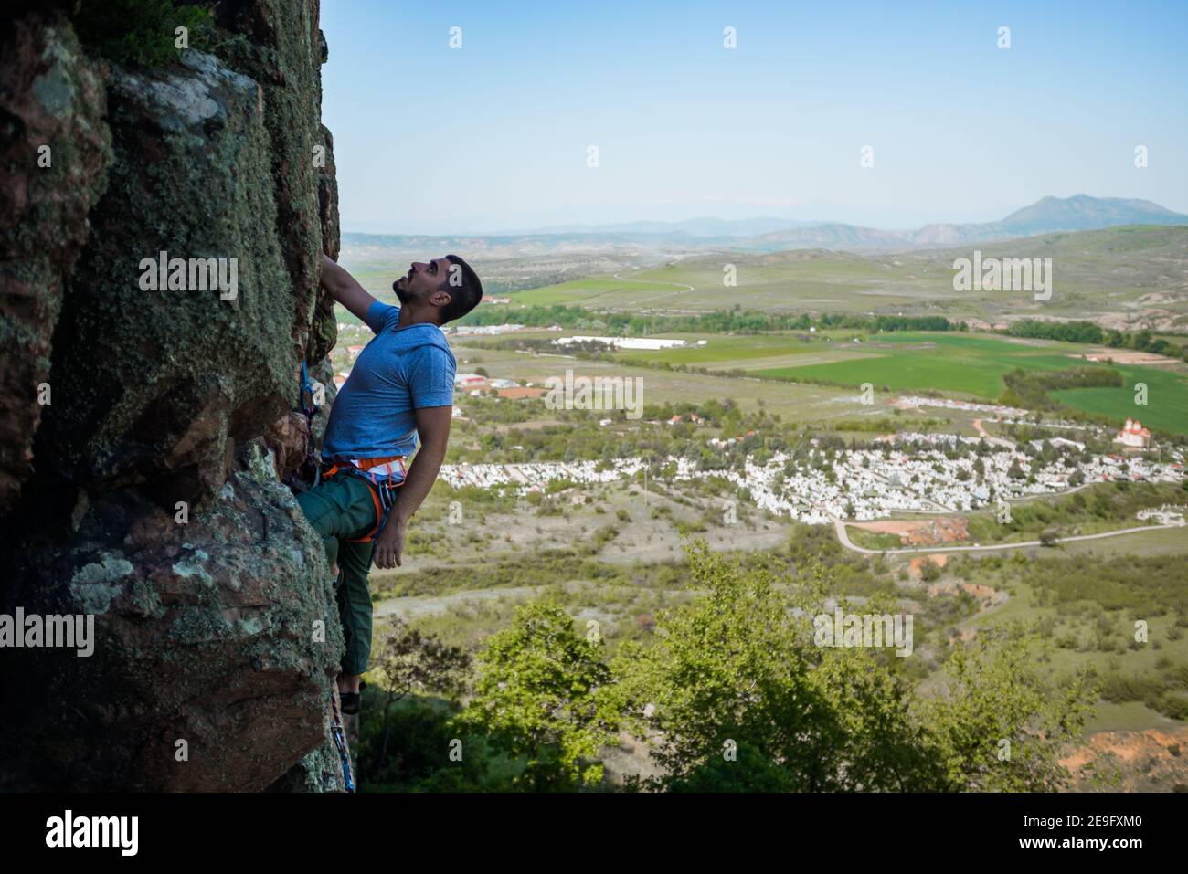 Man climbing a rock short before reaching the summit Stock Photo - Alamy
