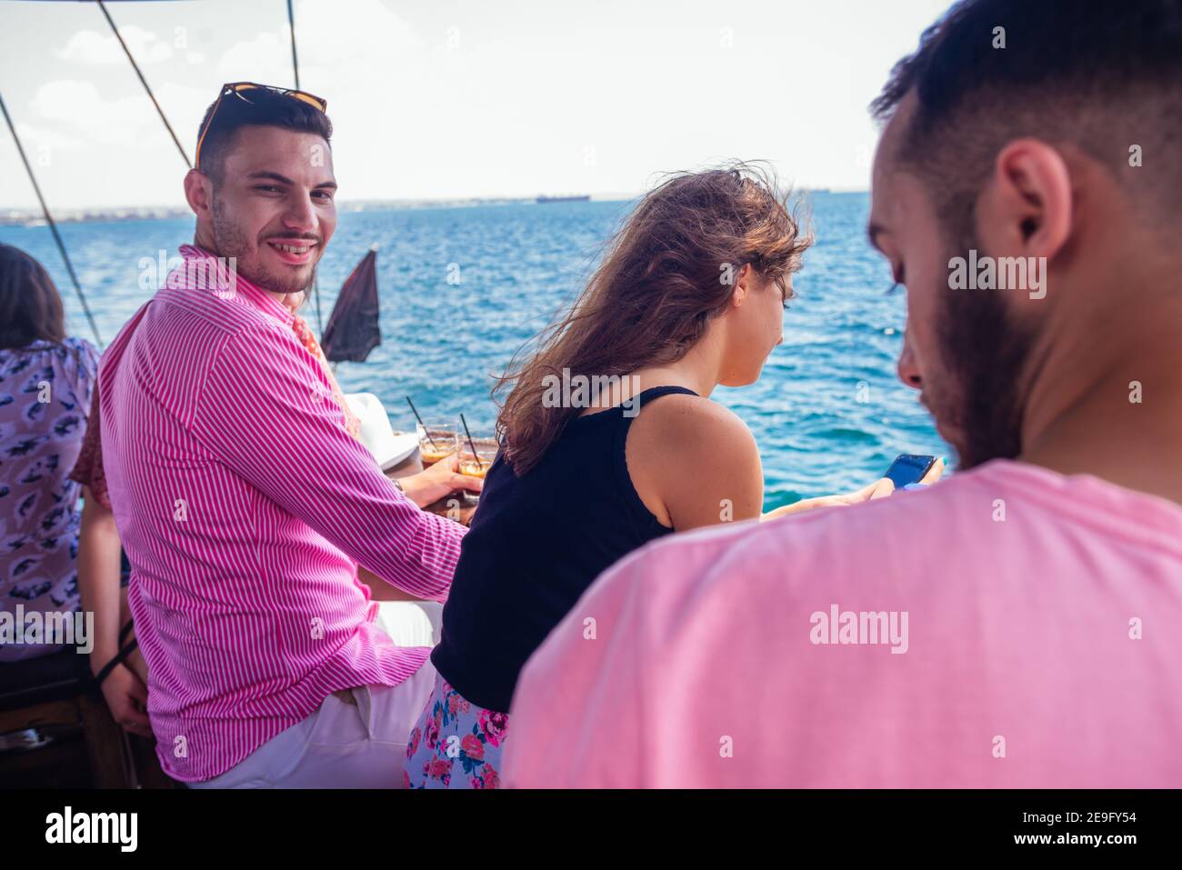 Three happy friends enjoying the sea view and the sunlight on a boat ...