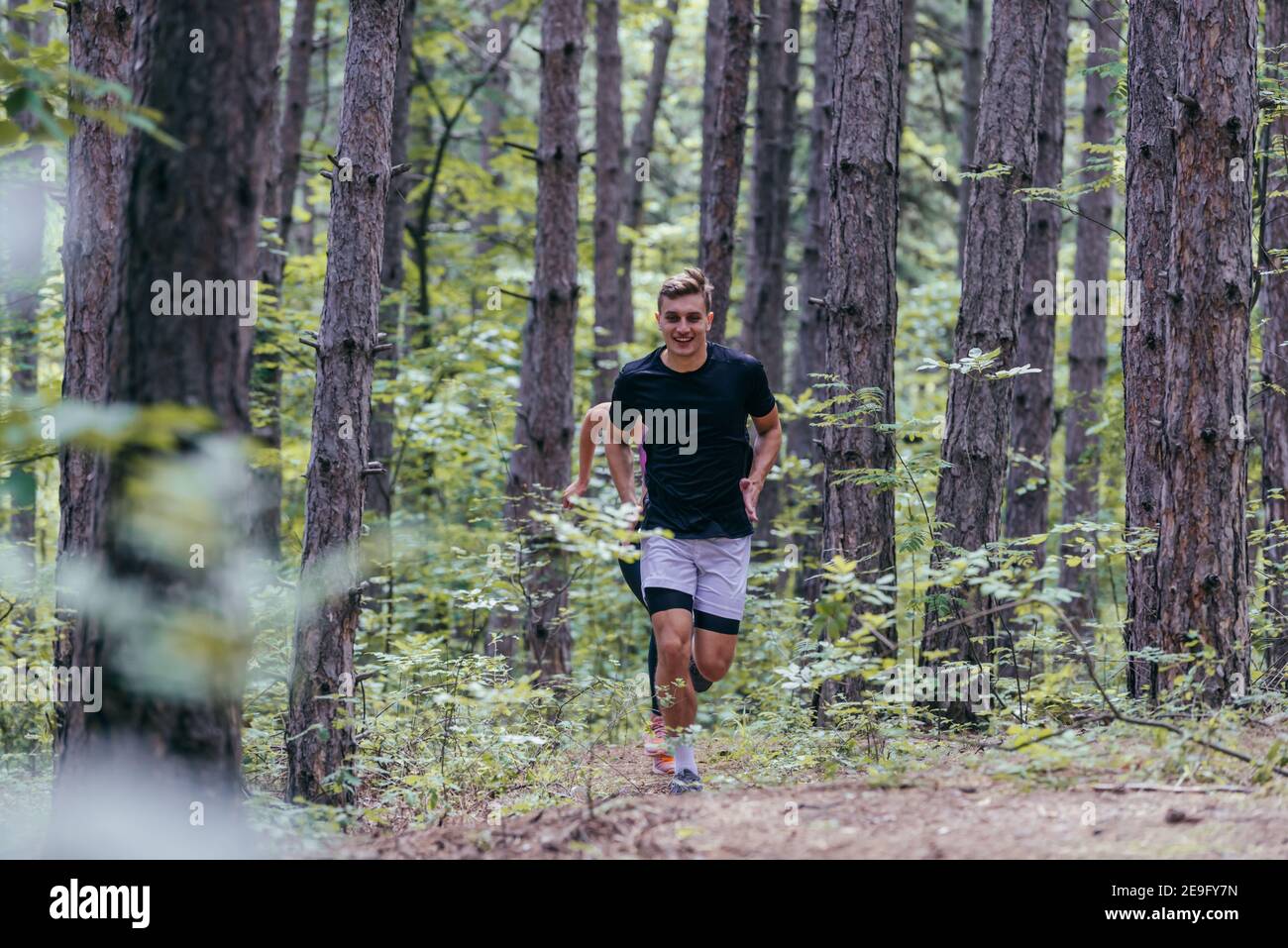 Strong male runner jogging for marathon on forest road Stock Photo - Alamy