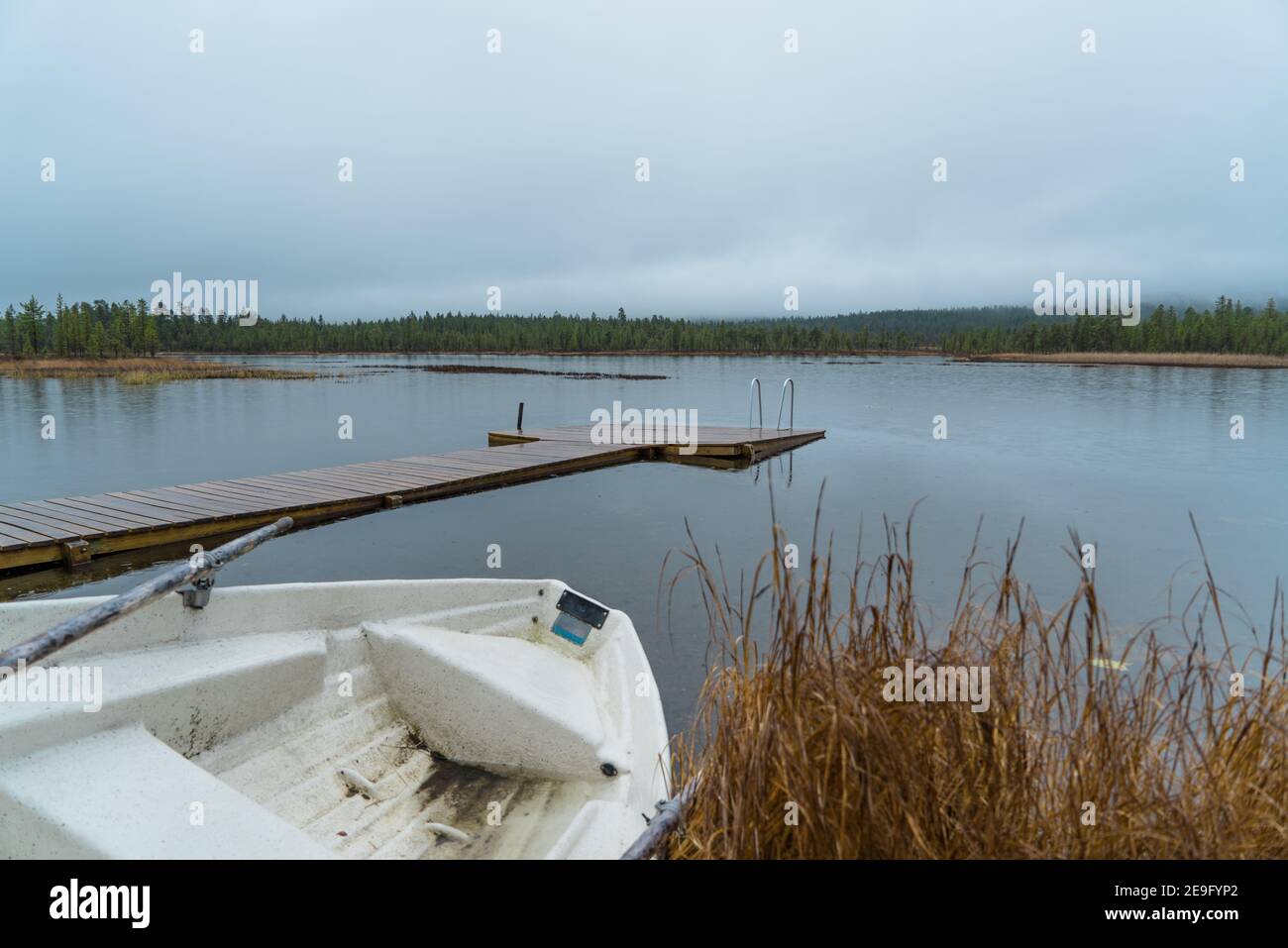 Old, dirty, used rowing boat laying next to a typical small finish lake ...