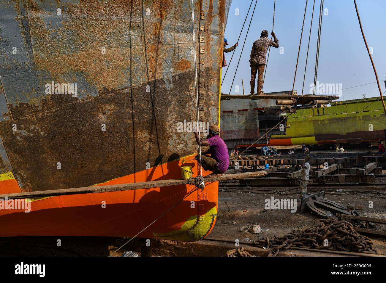 Dockyard workers carry on maintenance works on the hull of a ship on ...