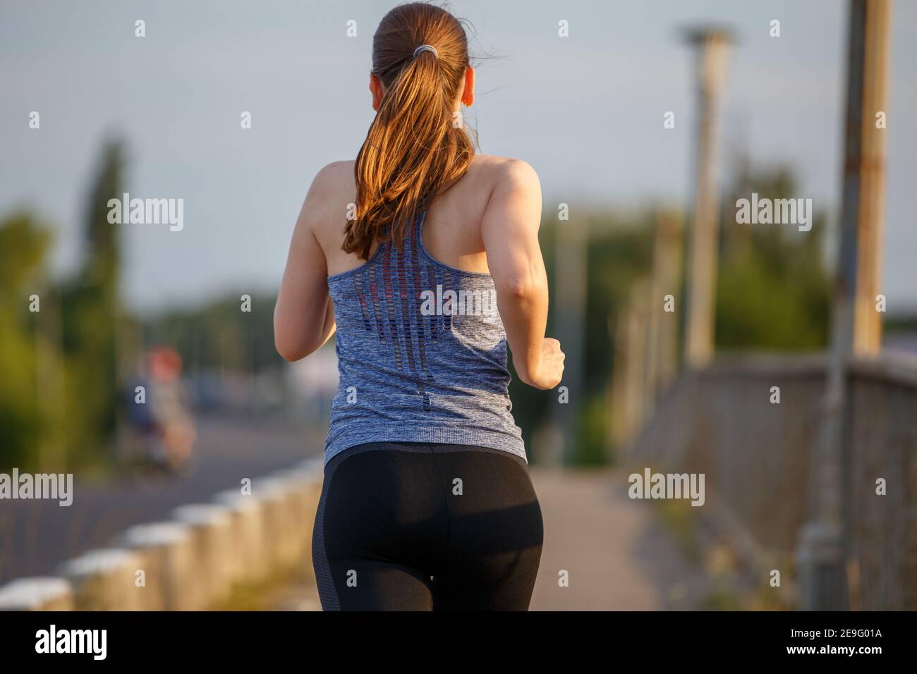 Back view of jogging young woman on the bridge Stock Photo - Alamy