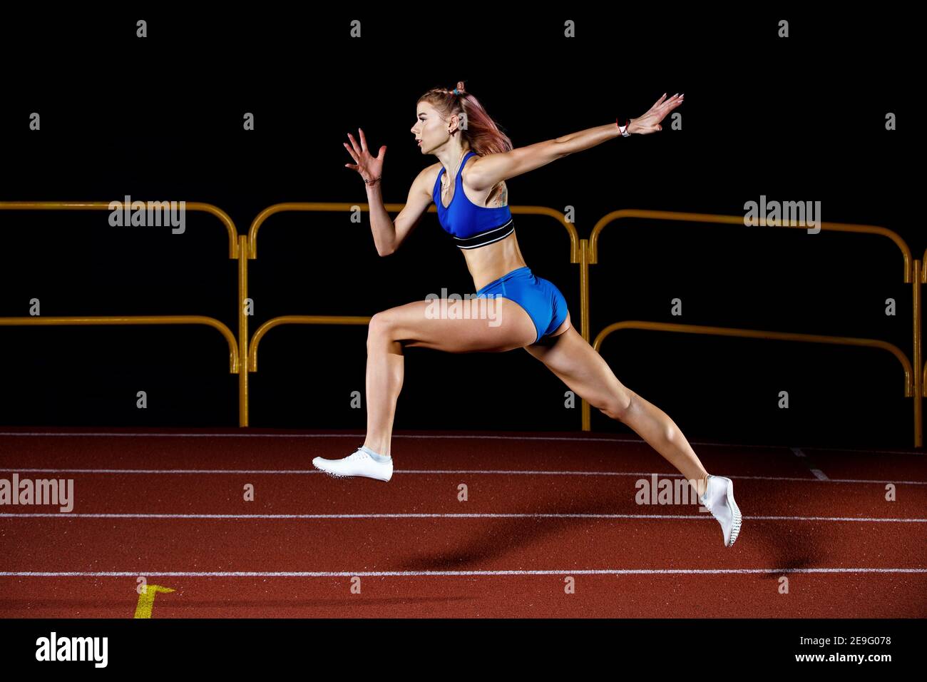 Sprinter girl jumps on track running training Stock Photo - Alamy