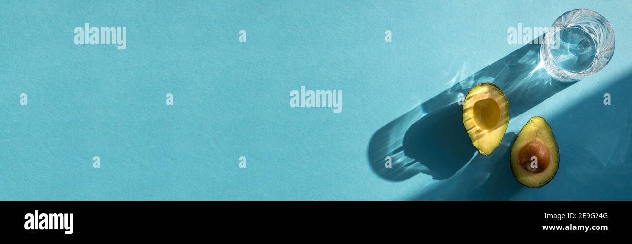 Oblong banner of two avocado halves isolated on turquoise coloured ...