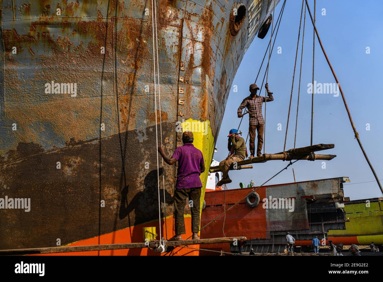 Dockyard workers carry on maintenance works on the hull of a ship on ...