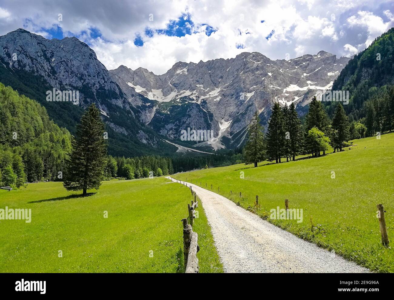 Beautiful alpine valley, gravel road, green meadows surrounded by ...