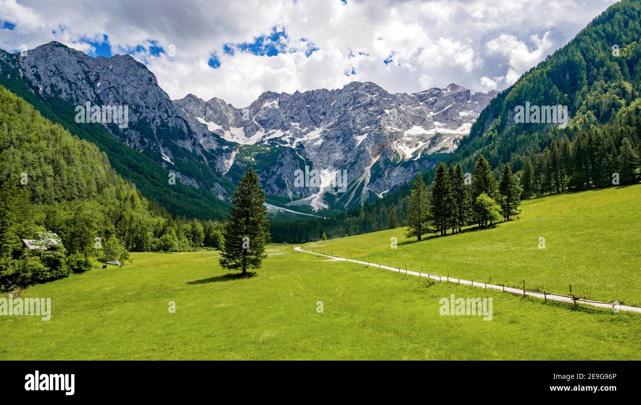 Beautiful alpine valley, gravel road, green meadows surrounded by ...