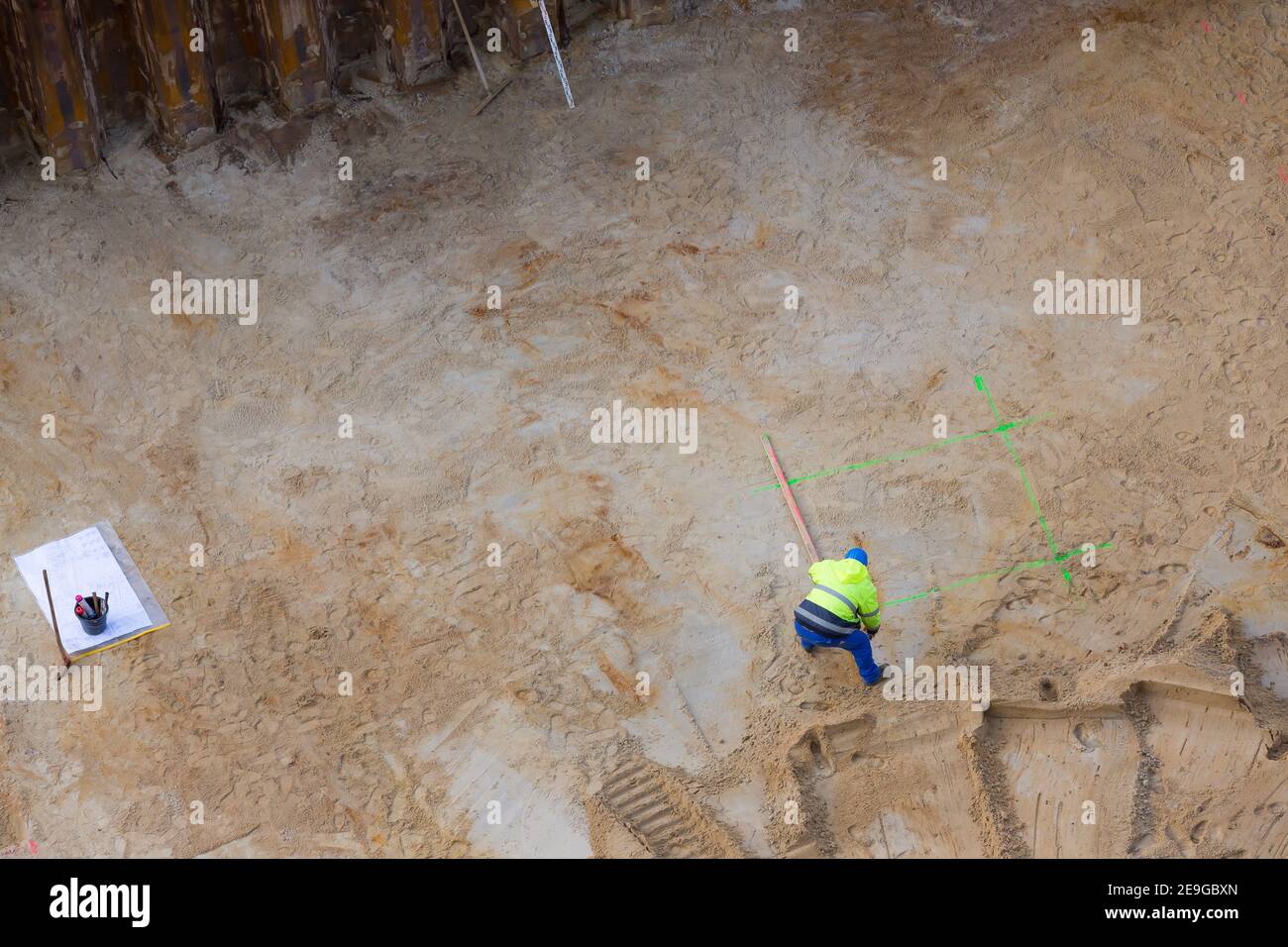 worker with safety vest marks the construction site with benchmark ...