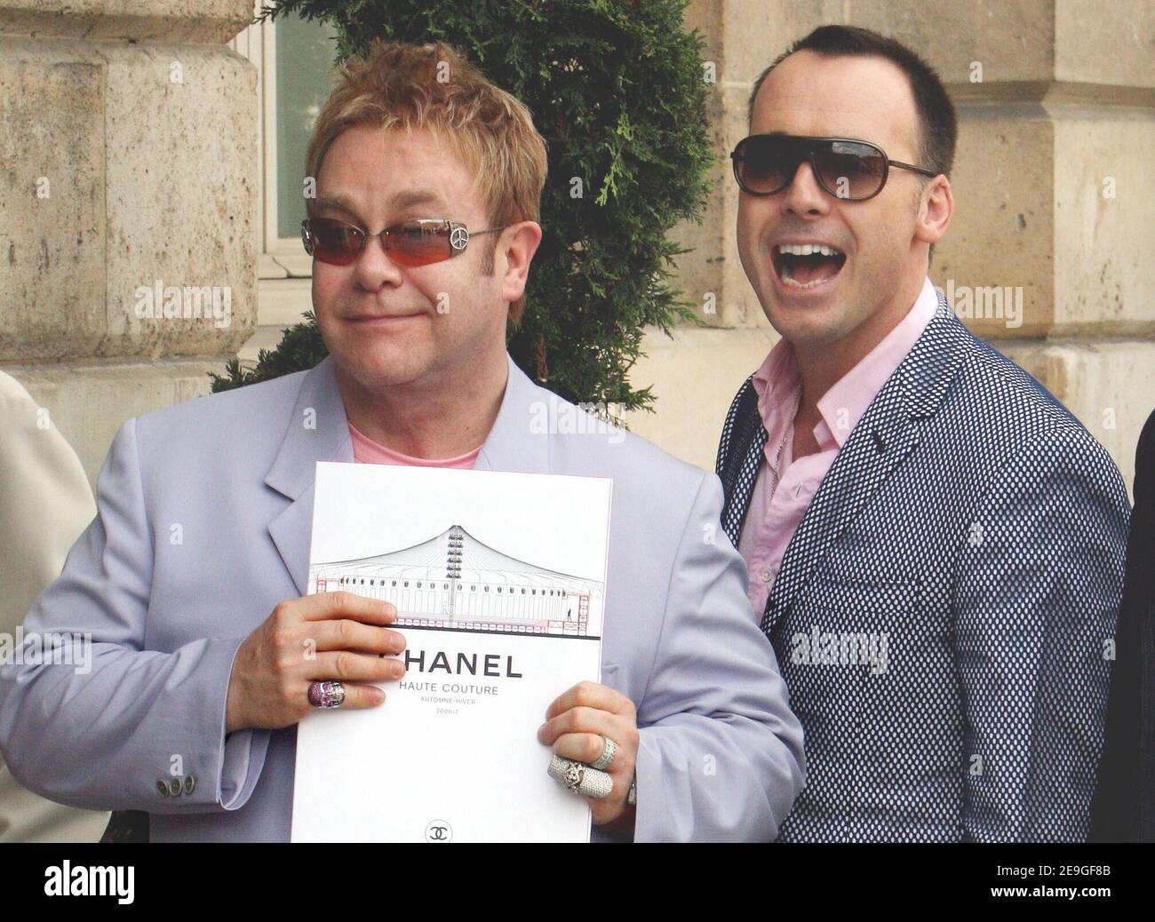 Elton John and his partner David Furnish show their Chanel invitation ...