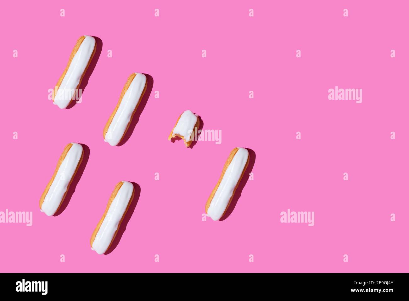 An eclair with the white topping on the pink background pattern concept ...