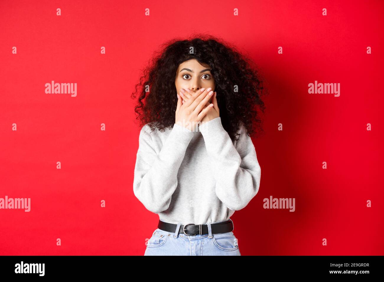 Image of speechless caucasian woman covering mouth with hands, looking ...