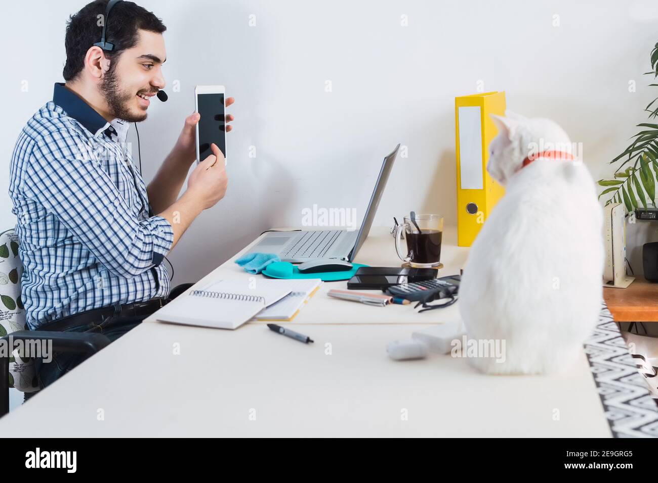 Male presenting in a video conference while his cat is sitting on the ...