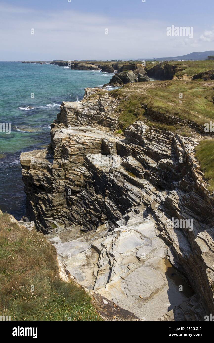 Vertical shot of a stone shore at the beach washed by blue ocean waves ...
