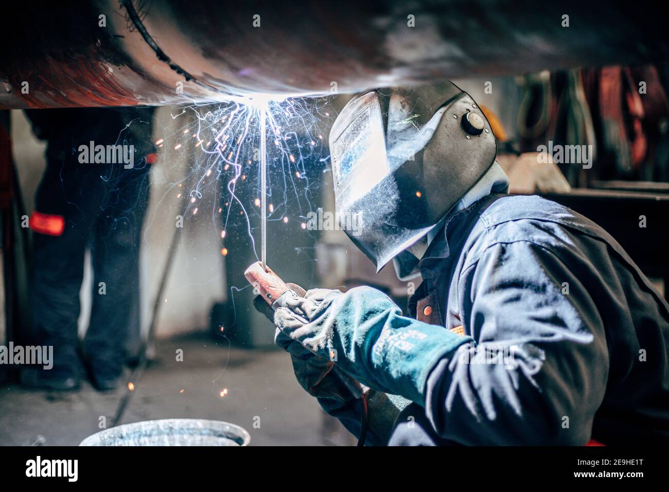 Shallow focus of a welder wearing a protective helmet and welding steel ...