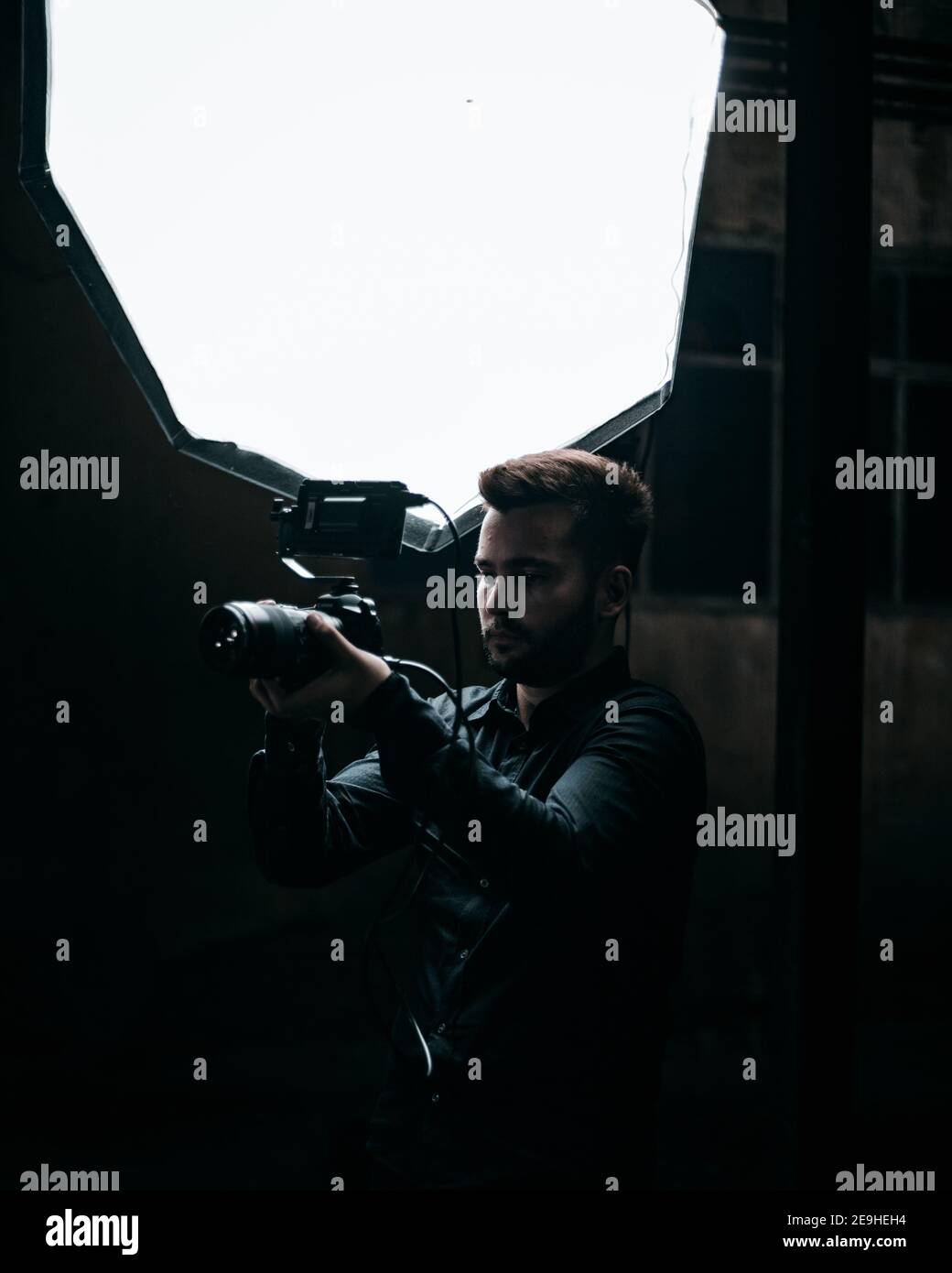 Shallow focus of an adult cameraman filming in a studio with a dark ...